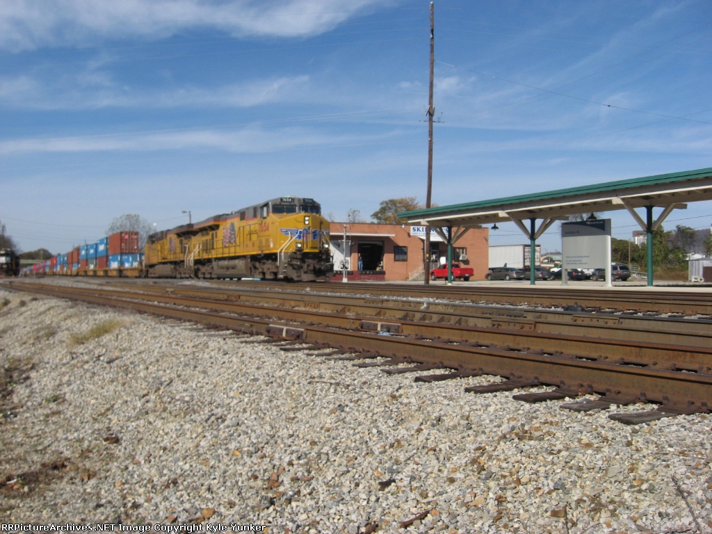 UP 7654 leads the coast to coast intermodal train past the Amtrak station